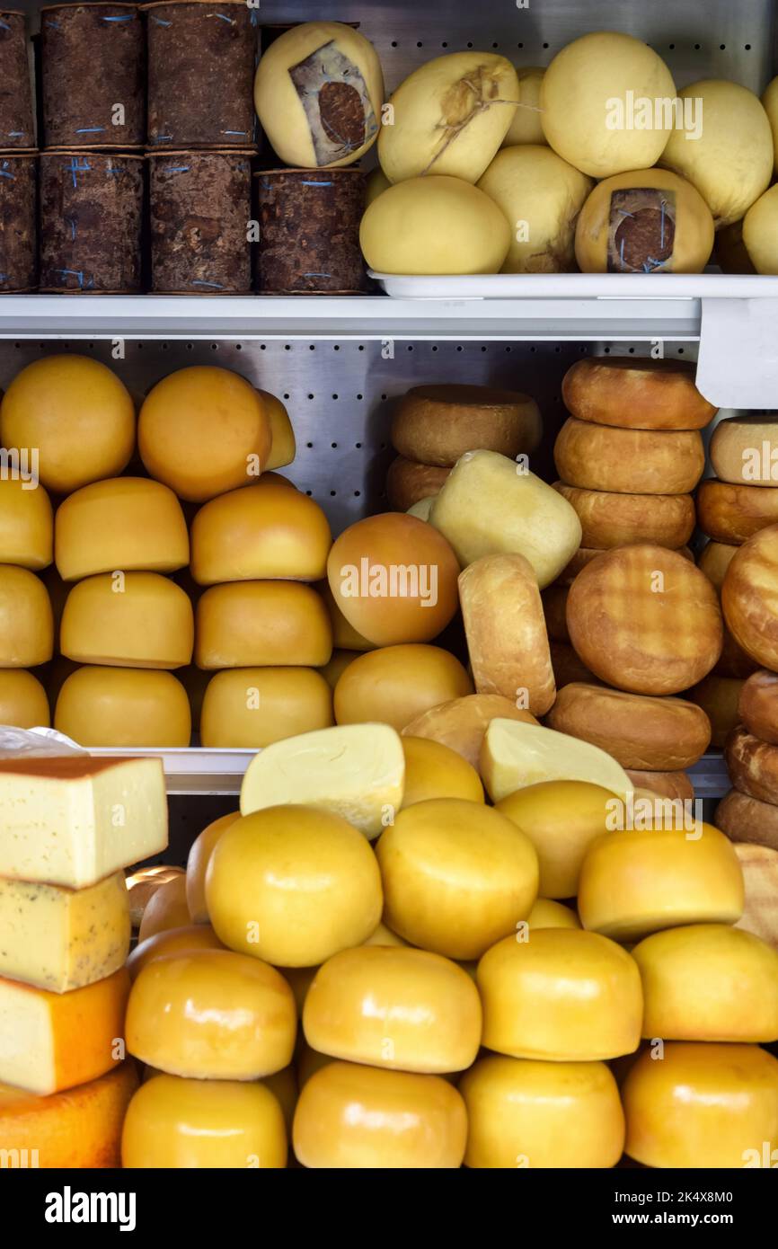 Cheese heads of different colors and sizes are stacked on counter. Fair ...