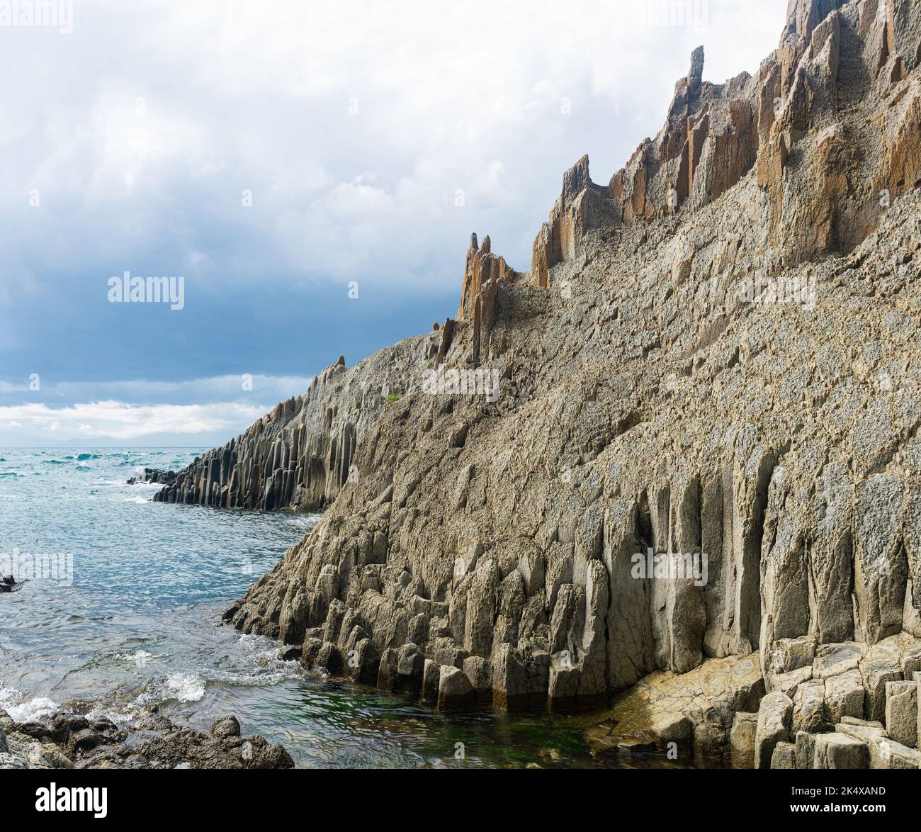 ocean shore with rocks of columnar basalt, Cape Stolbchaty on Kunashir ...