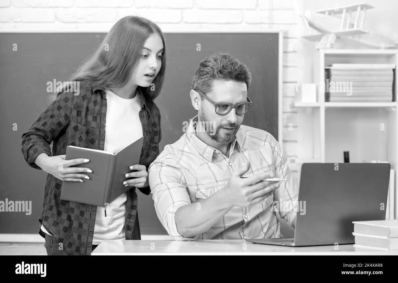 curious kid and dad sitting in classroom with copybook and computer at ...