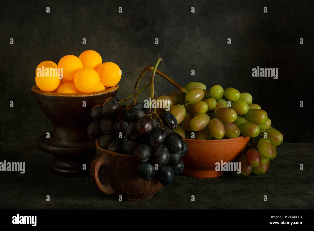 Still life with ripe grapes and orange balls Stock Photo - Alamy
