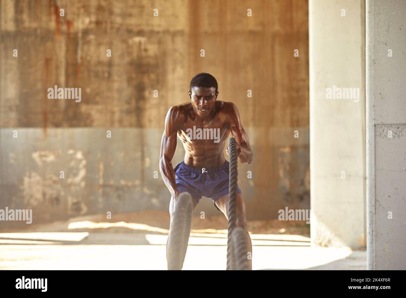 Rope workout. Sport man doing battle ropes exercise outdoor. Black male ...