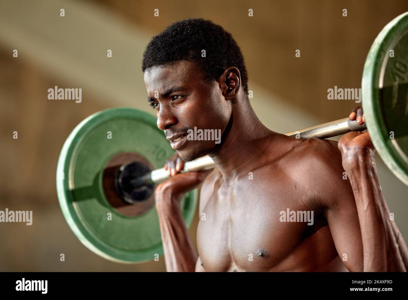 Athletic black young man lifting a heavy-weight barbell in outdoor gym ...