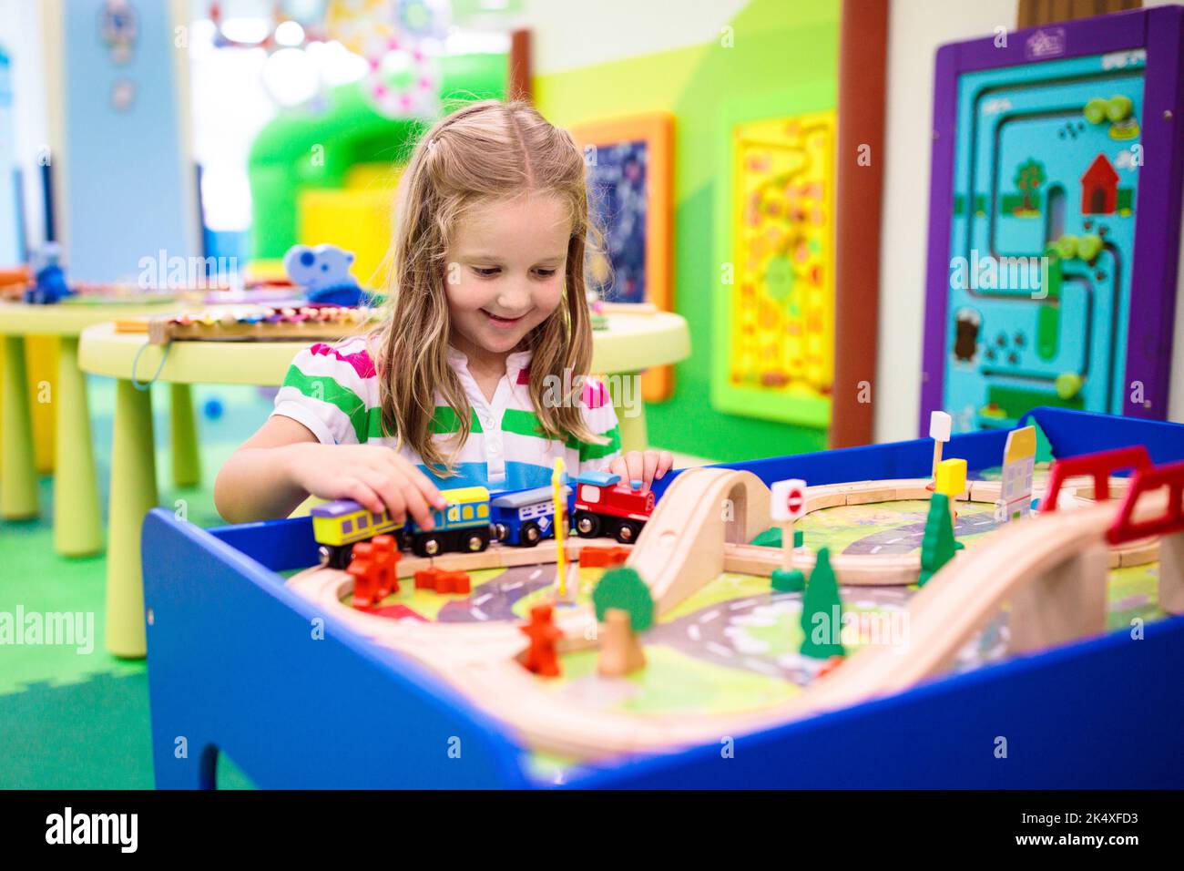 Kids play toy railroad. Little blond curly boy with wooden trains in ...