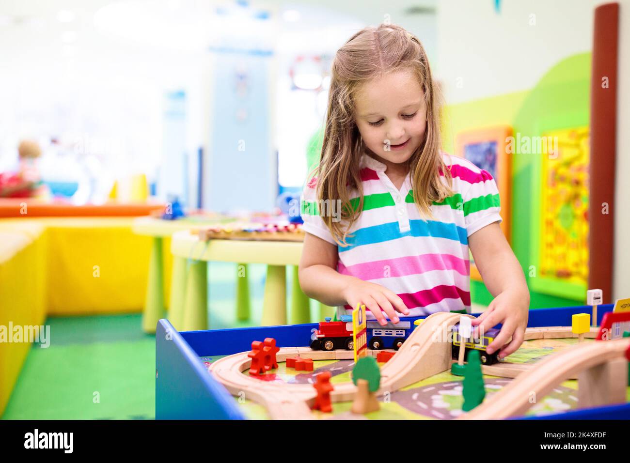 Kids play toy railroad. Little blond curly boy with wooden trains in ...