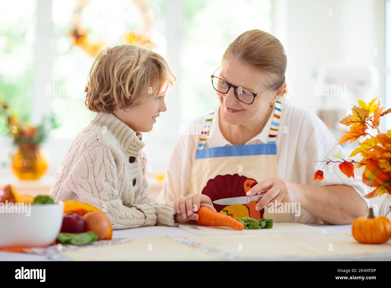 Family cooking Thanksgiving dinner. Grandmother and child cut pumpkin ...