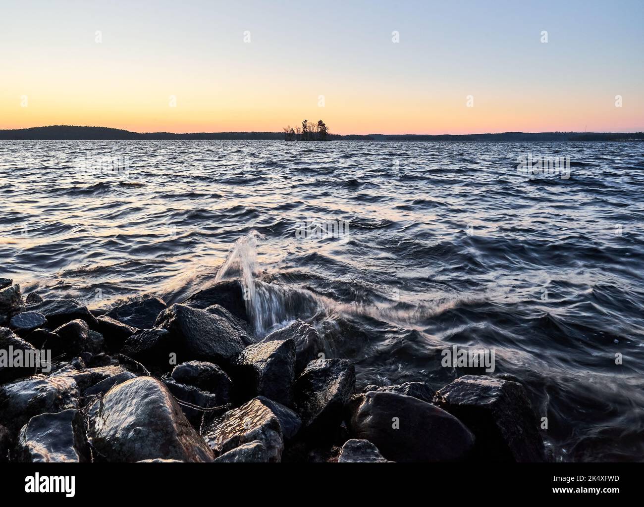 A beautiful view of a lake with stones on a shore during sunrise Stock ...