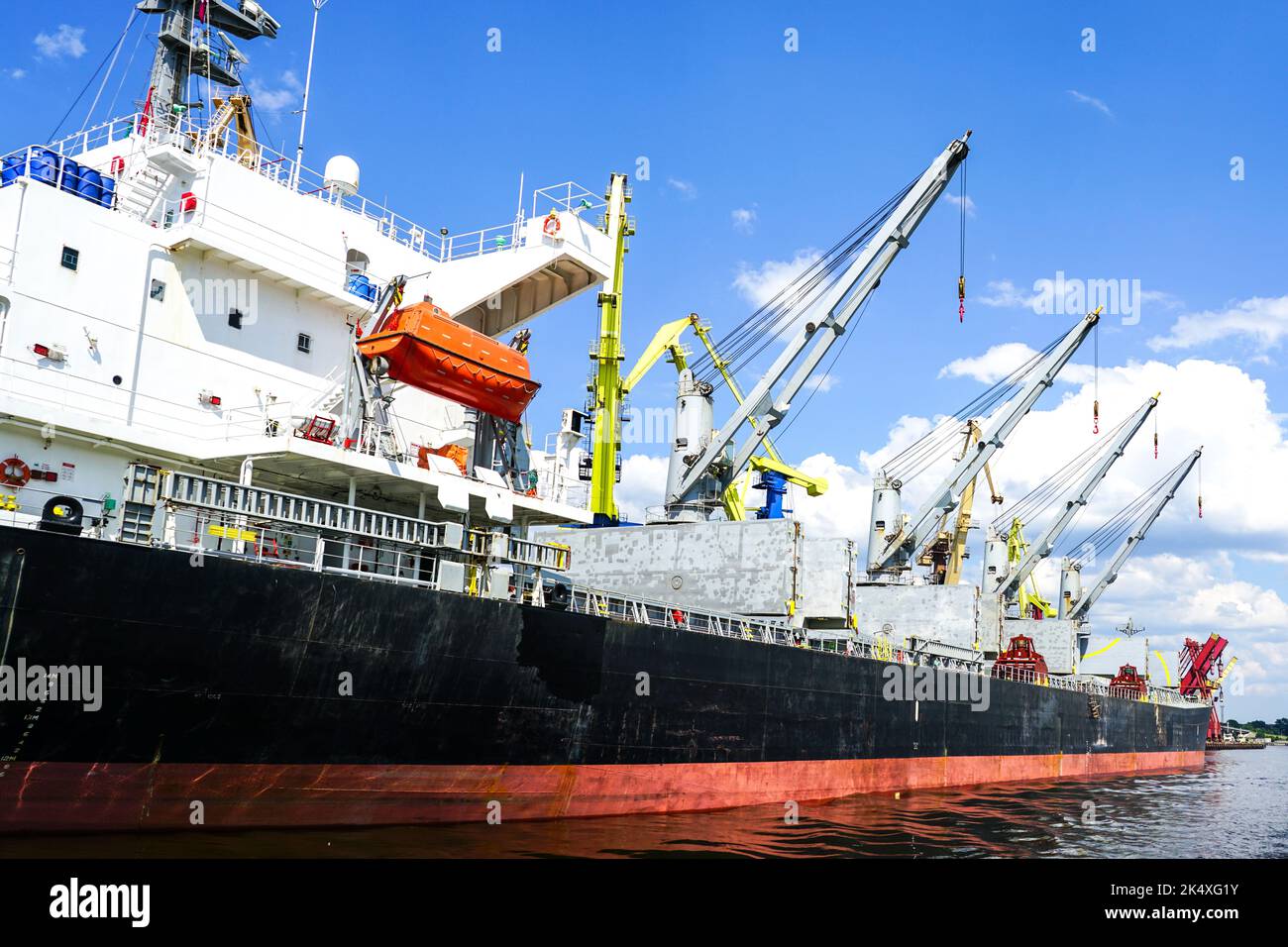 Large bulk carrier with open holds in harbor cargo terminal, shore ...
