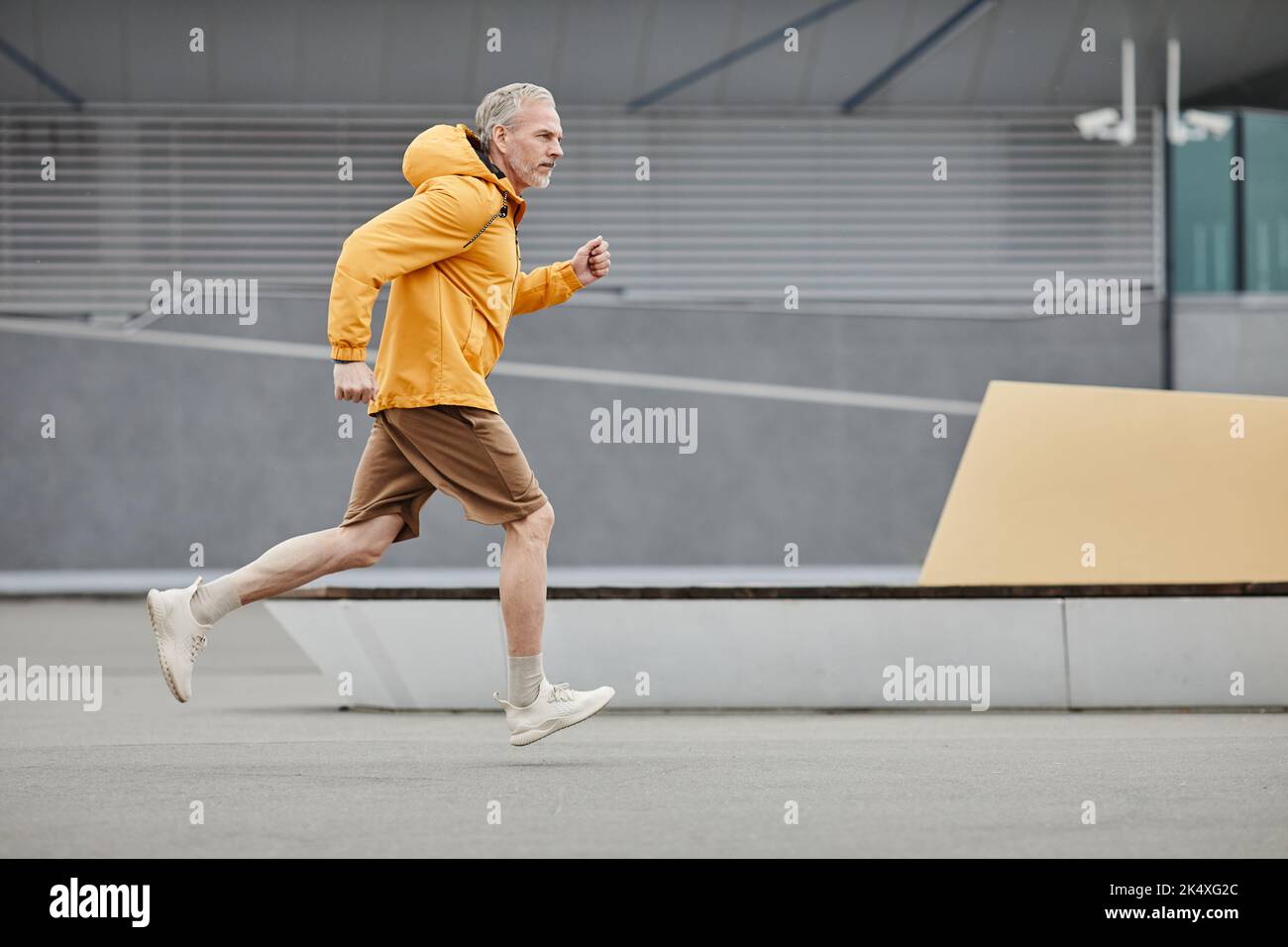 Side view portrait of sportive senior man running fast outdoors in ...