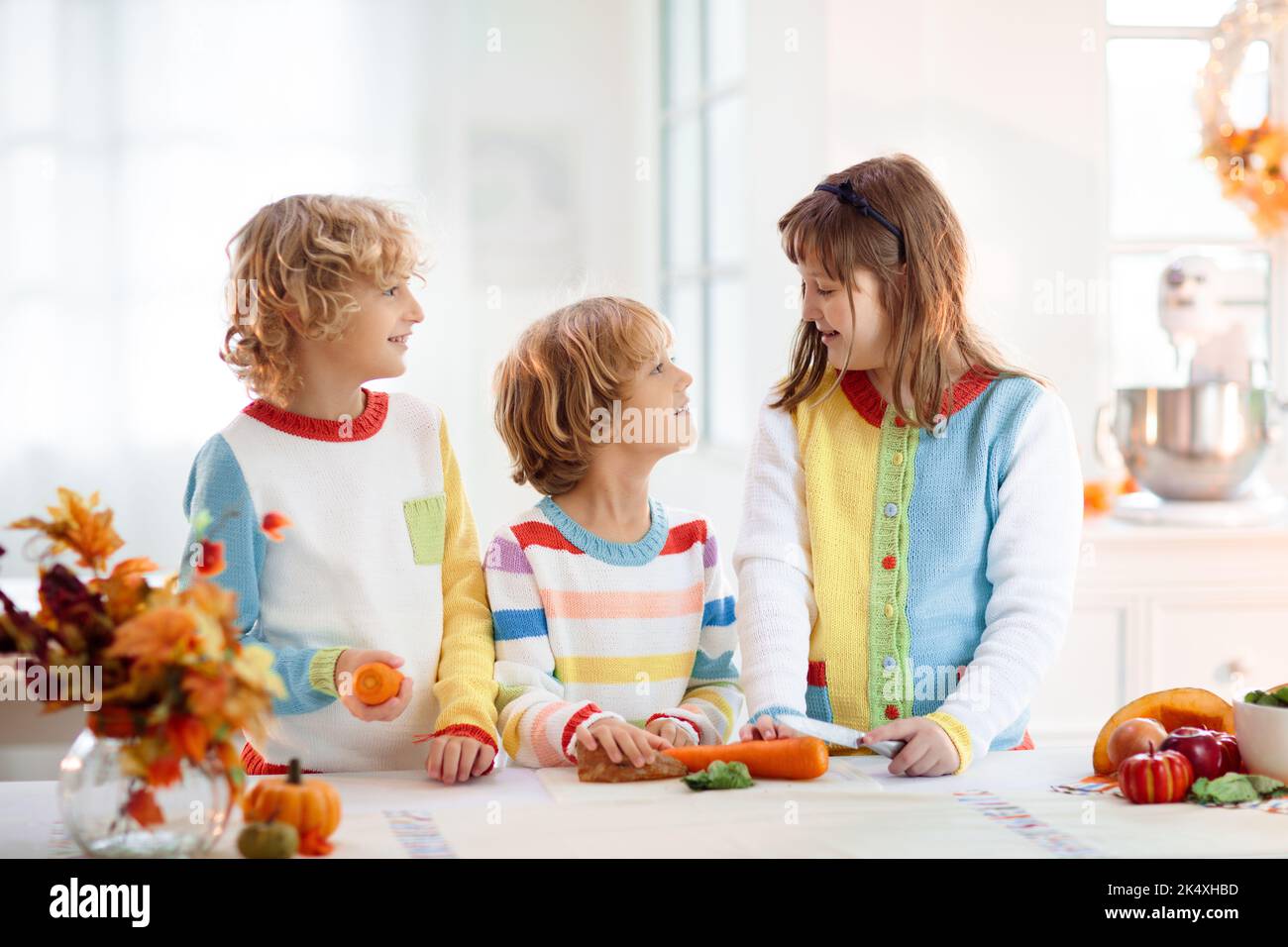 Family cooking Thanksgiving dinner. Children cut pumpkin in decorated ...