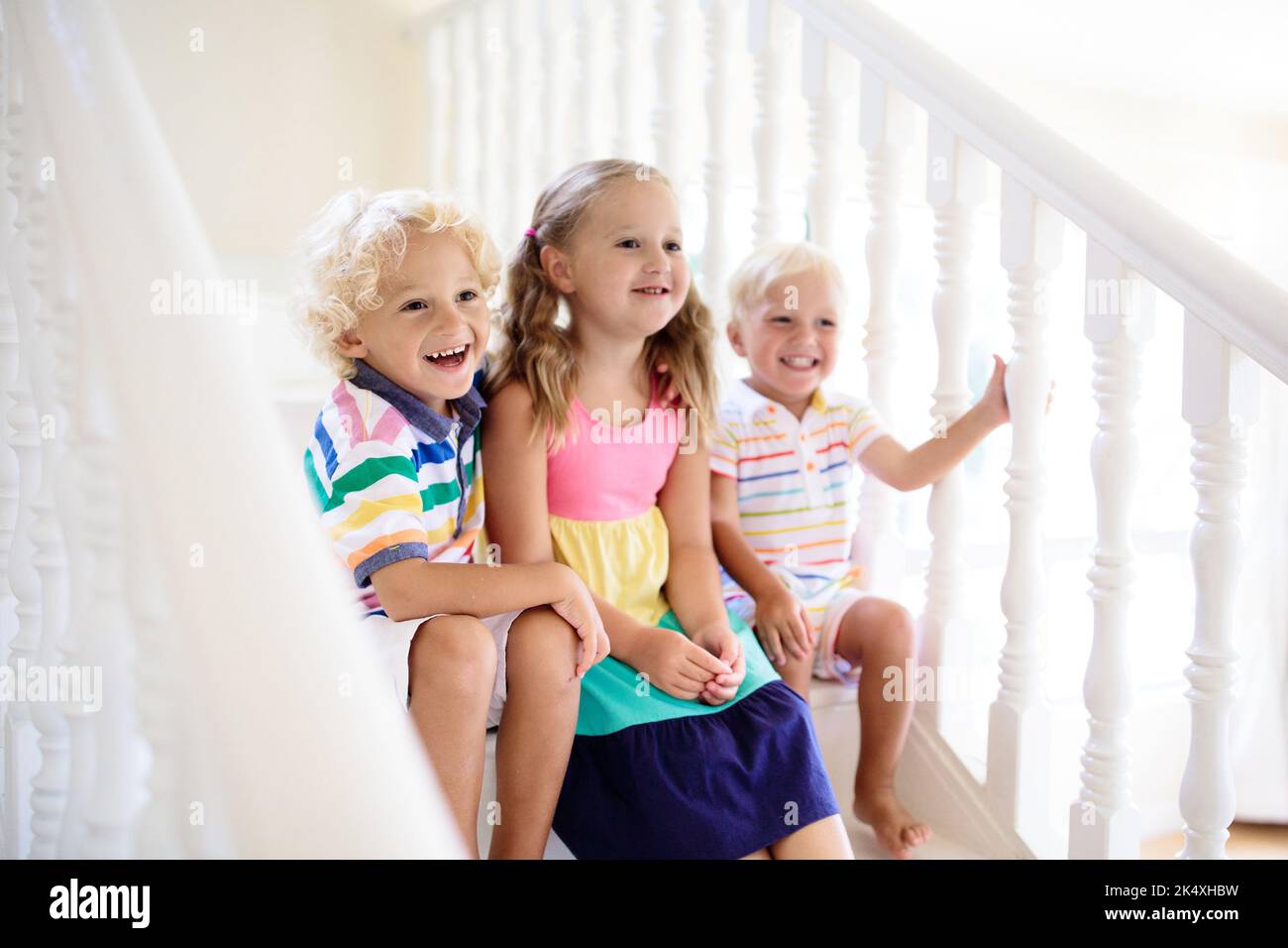 Kids walking stairs in white house. Children playing in sunny staircase ...