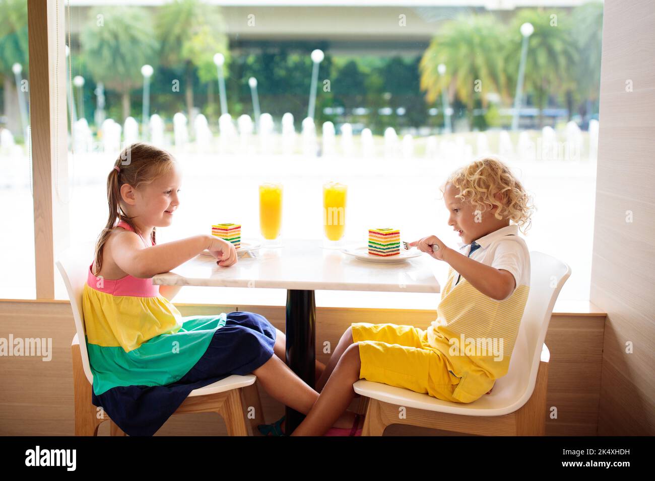 Kids eat rainbow cake at restaurant. Boy and girl with sweets and ...