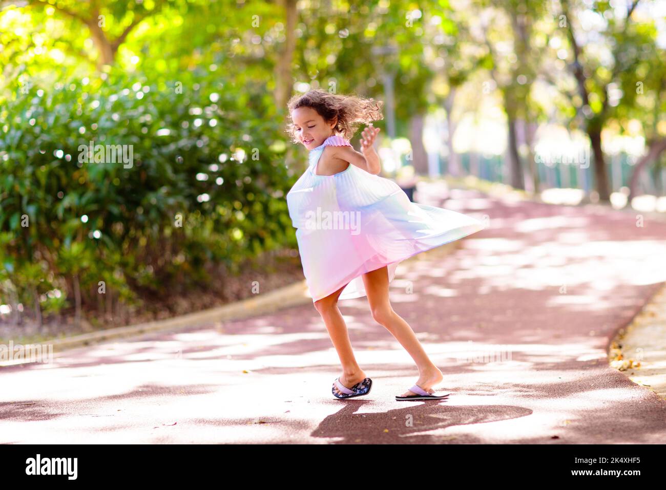 Happy kid playing in summer park. Little girl dancing in beautiful ...