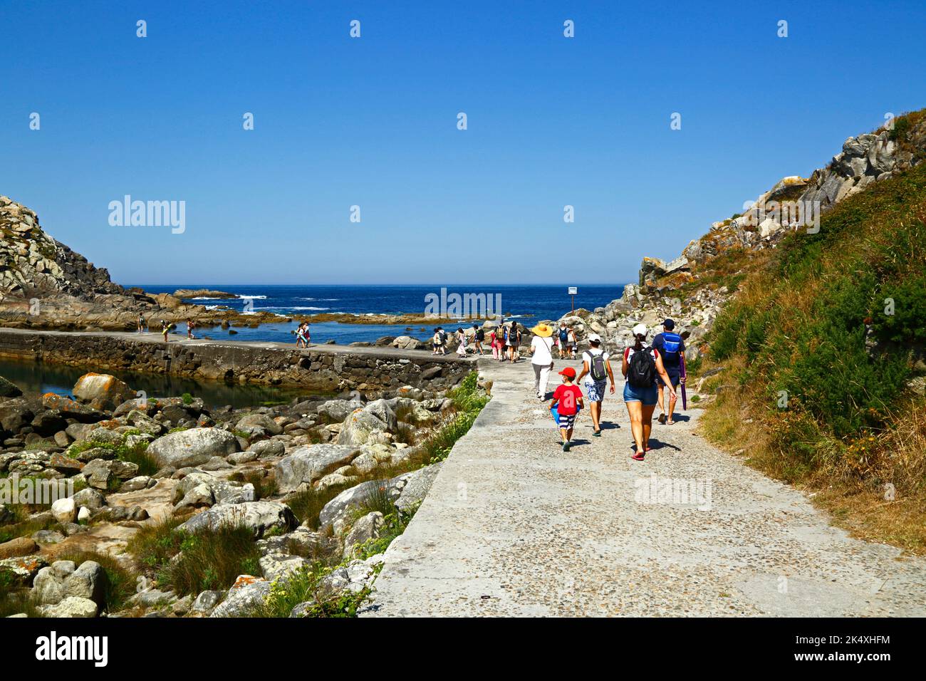 Tourists walking along causeway across tidal lagoon from Illa de ...