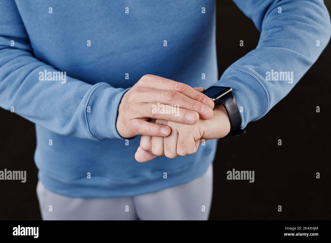 Minimal closeup of man checking smartwatch against black background ...