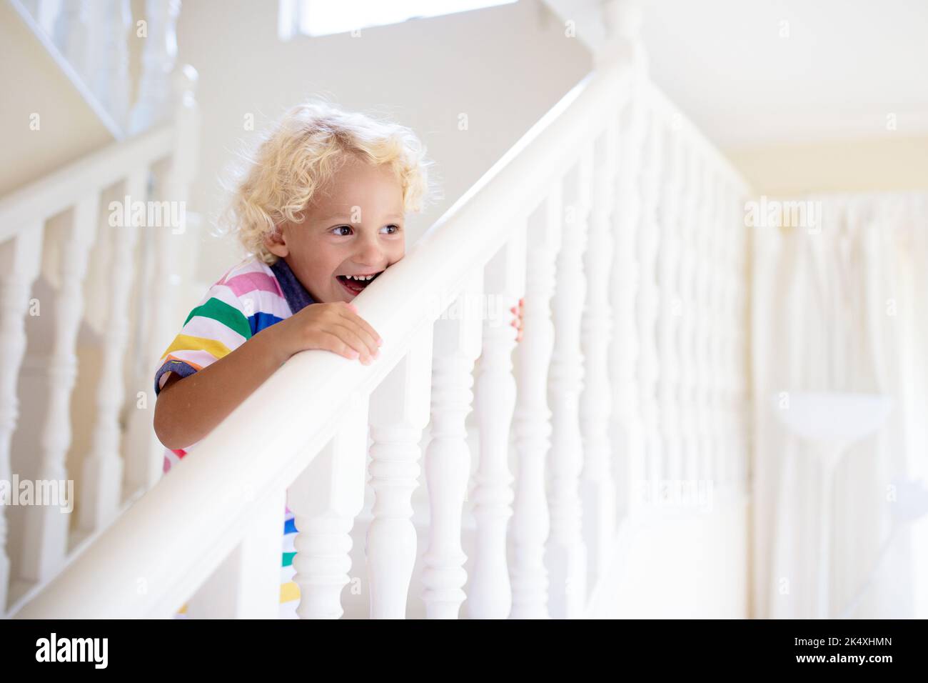 Kid walking stairs in white house. Little boy playing in sunny ...