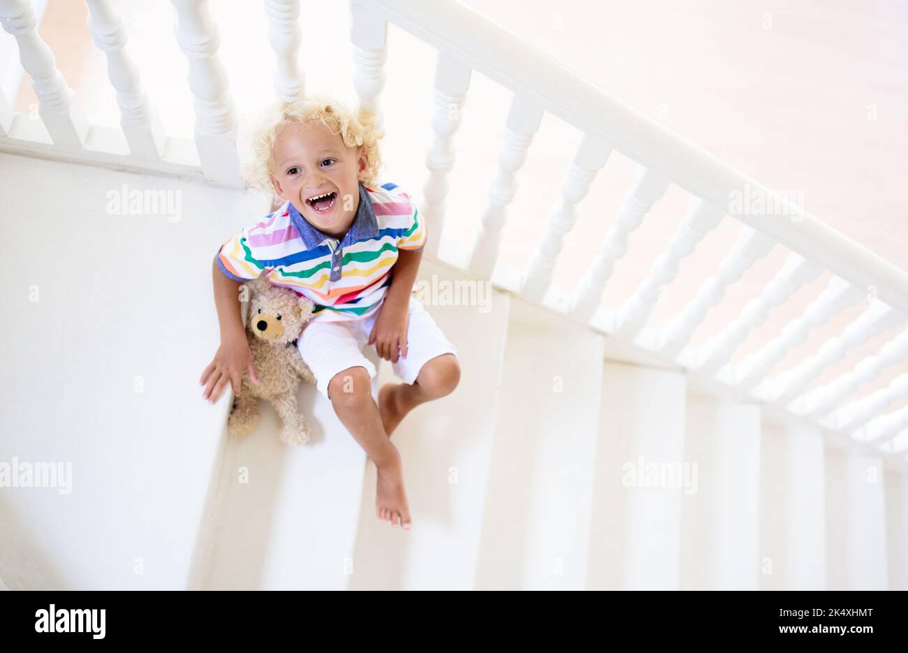 Kid walking stairs in white house. Little boy playing in sunny ...
