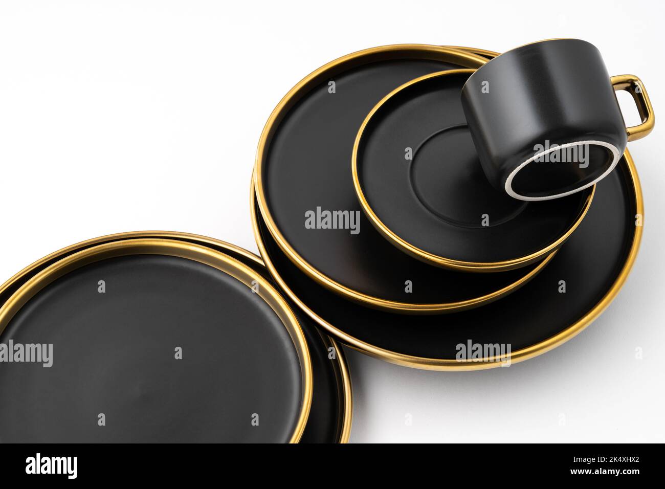 A Set of black and golden ceramic plates and cup on a white background ...