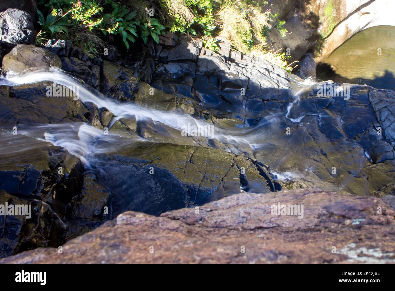Looking down at a waterfall where it flows down to a secluded pool ...
