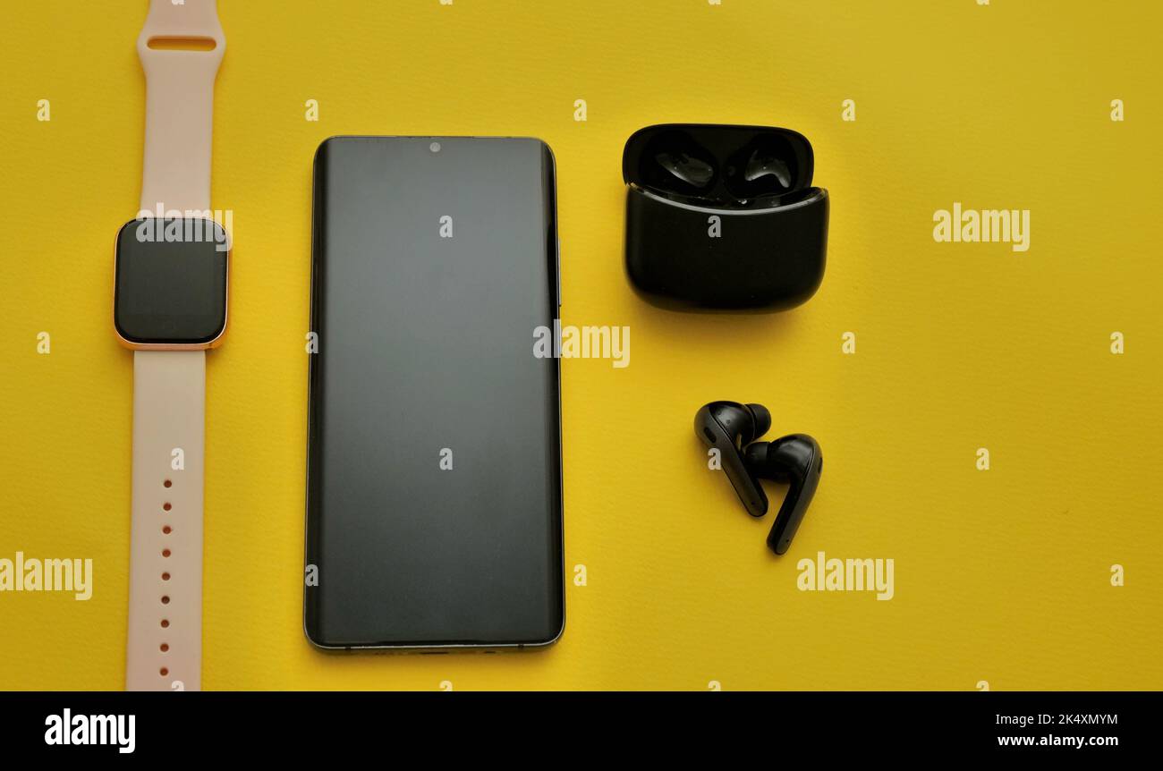Mockup of a smartphone on a yellow background. Headphones, smart watch ...