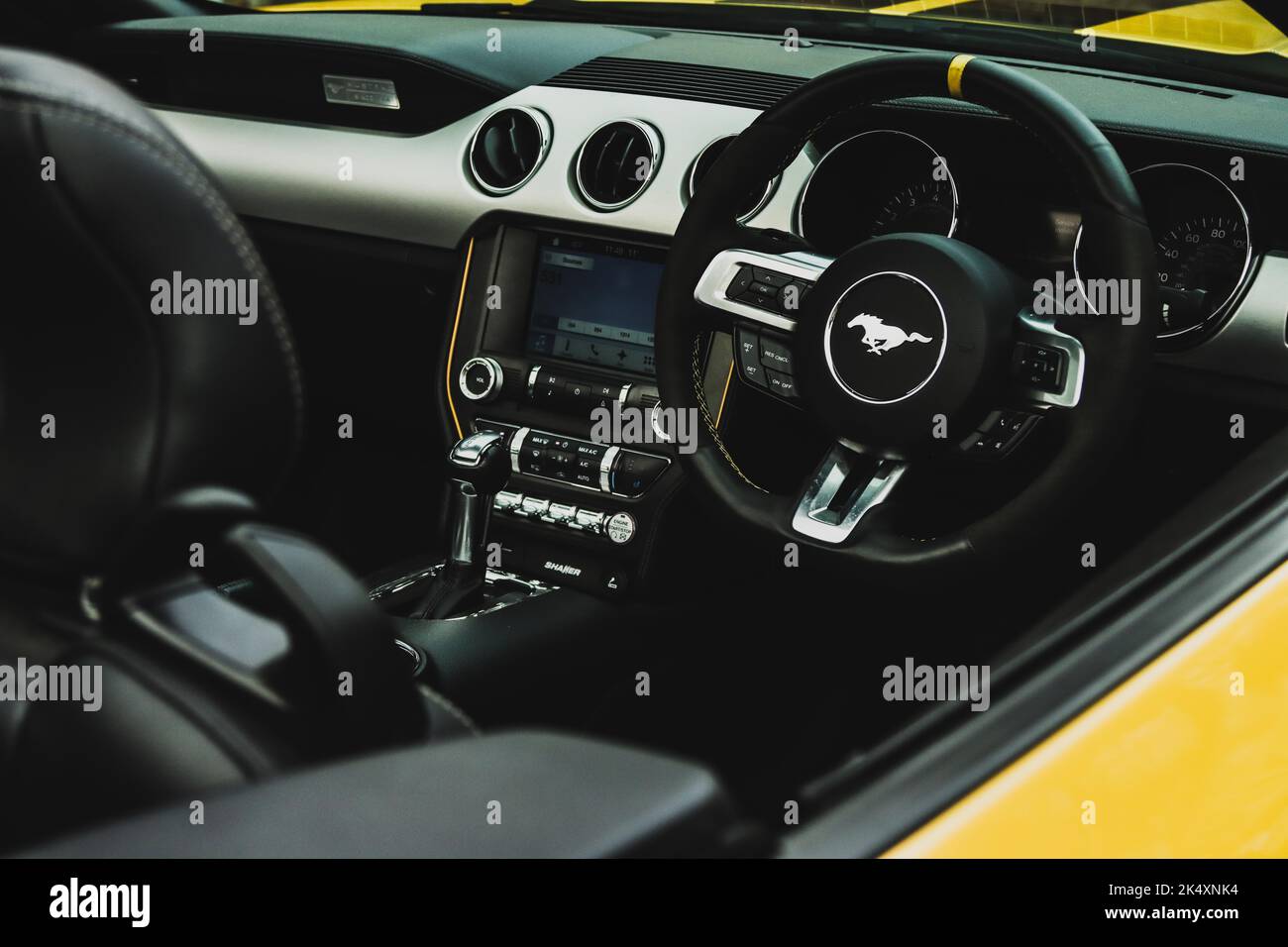 A yellow Ford Mustang interior with a digital screen and flat-bottom ...