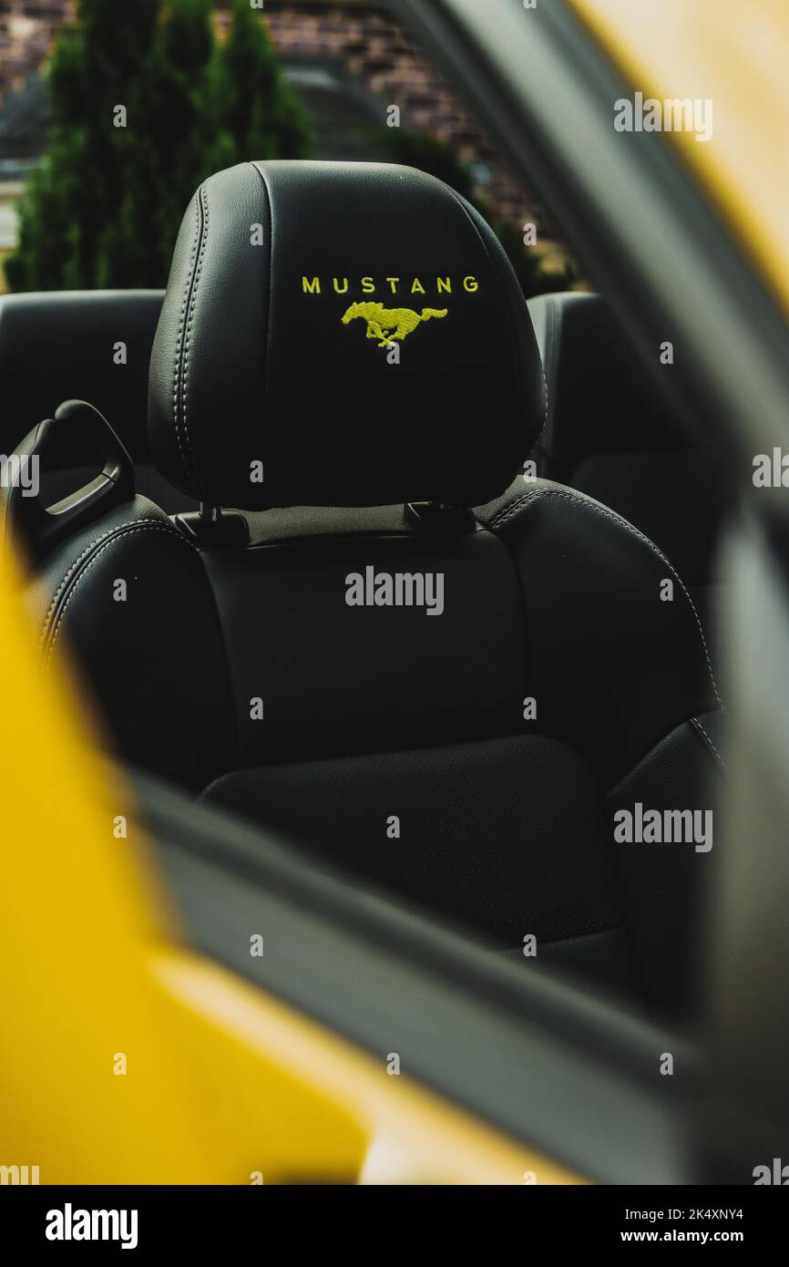 A close up of a yellow Ford Mustang seat with its logo on the headrest ...