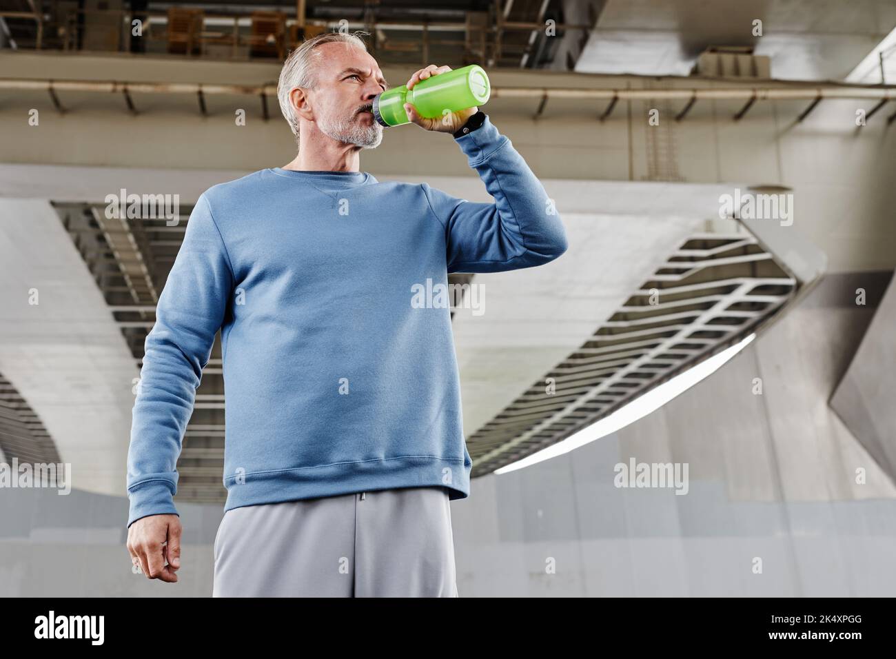 Low angle portrait of handsome senior man drinking water during outdoor ...