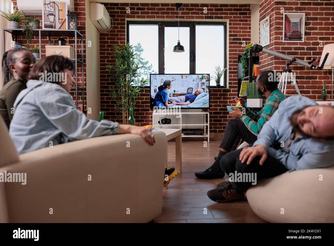 Men and women drinking beer and watching drama movie on tv, having fun together at gathering ...