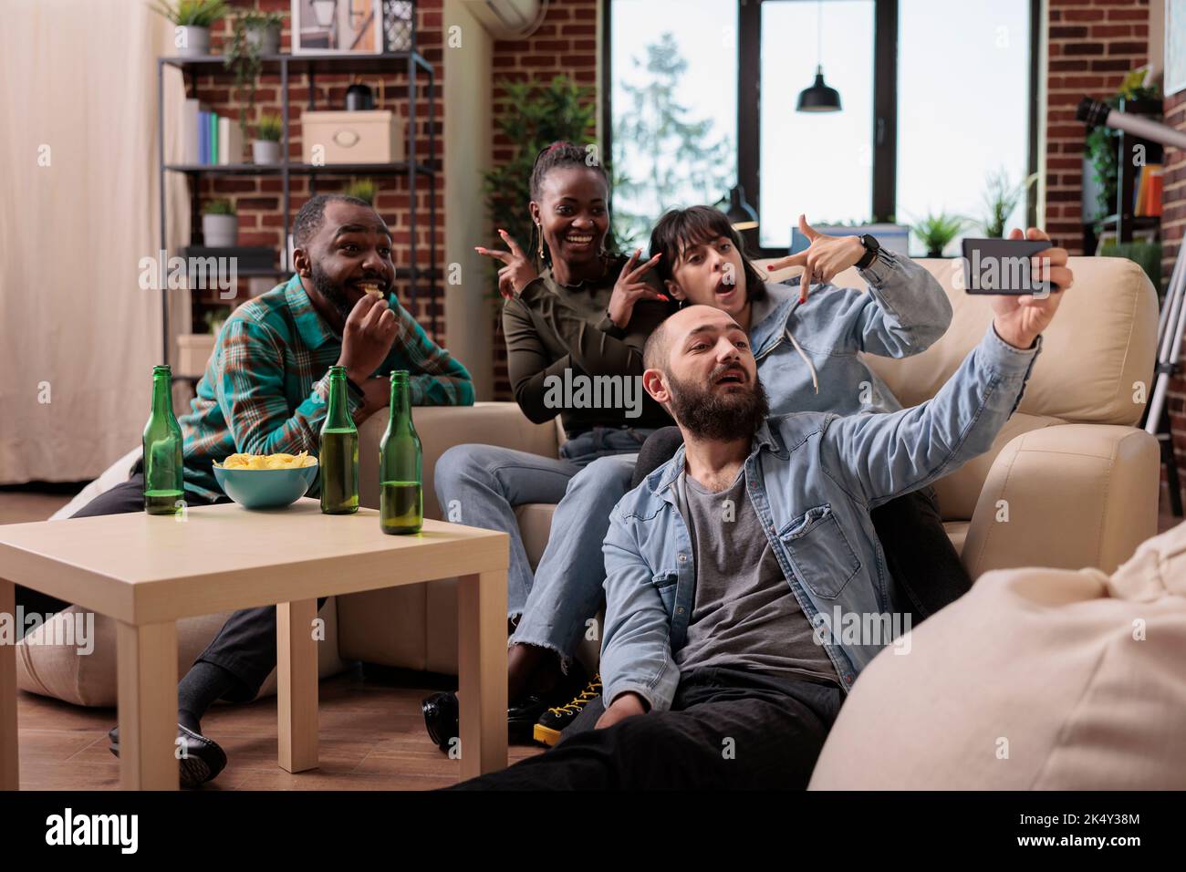Cheerful group of people taking pictures with smartphone at house party ...