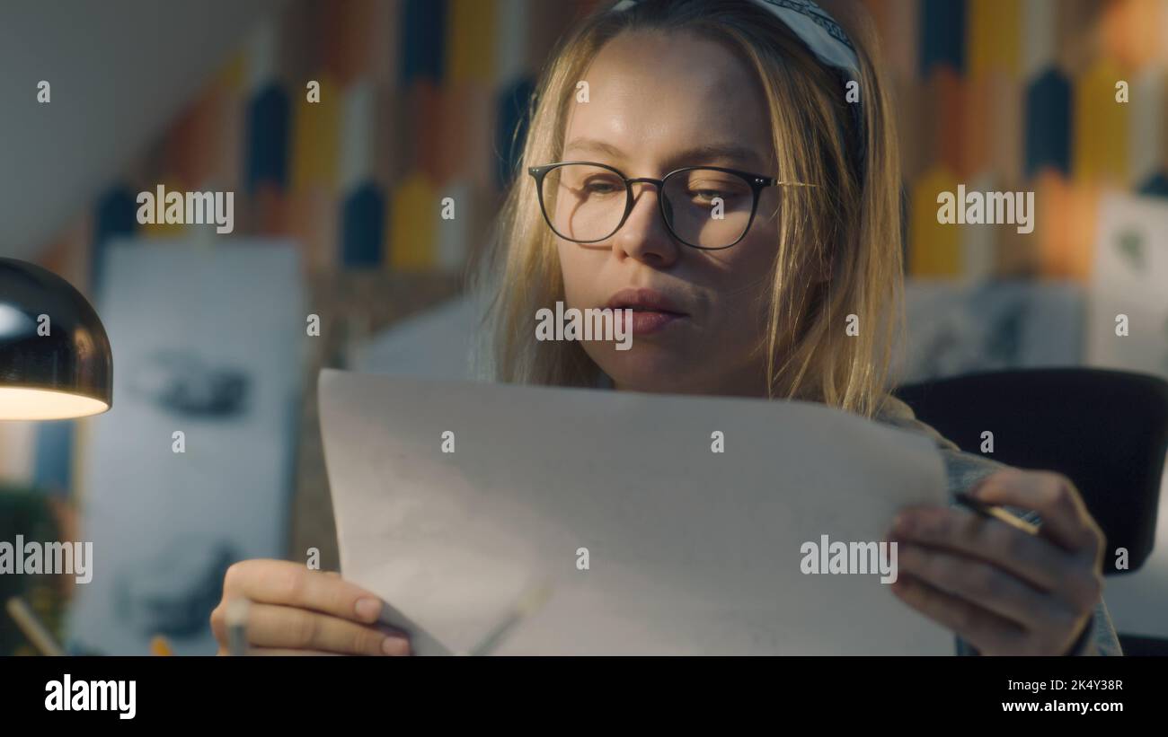 Female creative designer looks critically at her sketches for a comic ...