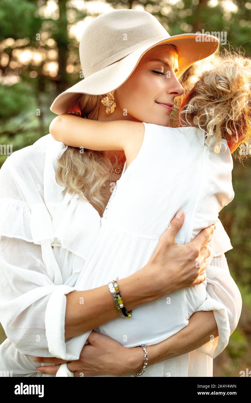 Vertical charming, kind, loving stylish woman in hat hugging little ...