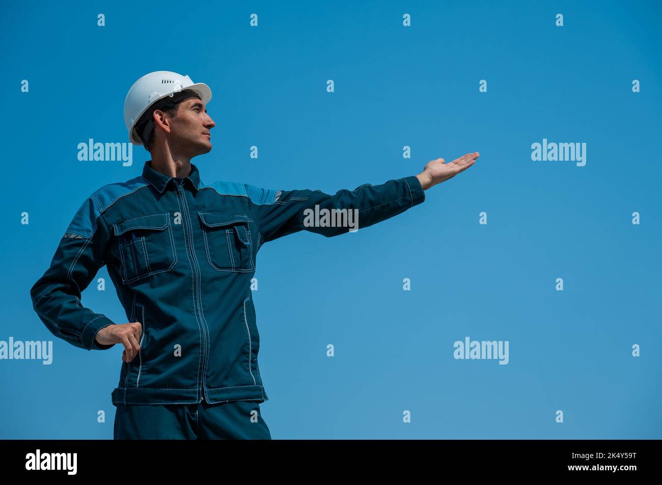 A caucasian man in work clothes and a construction helmet stands ...