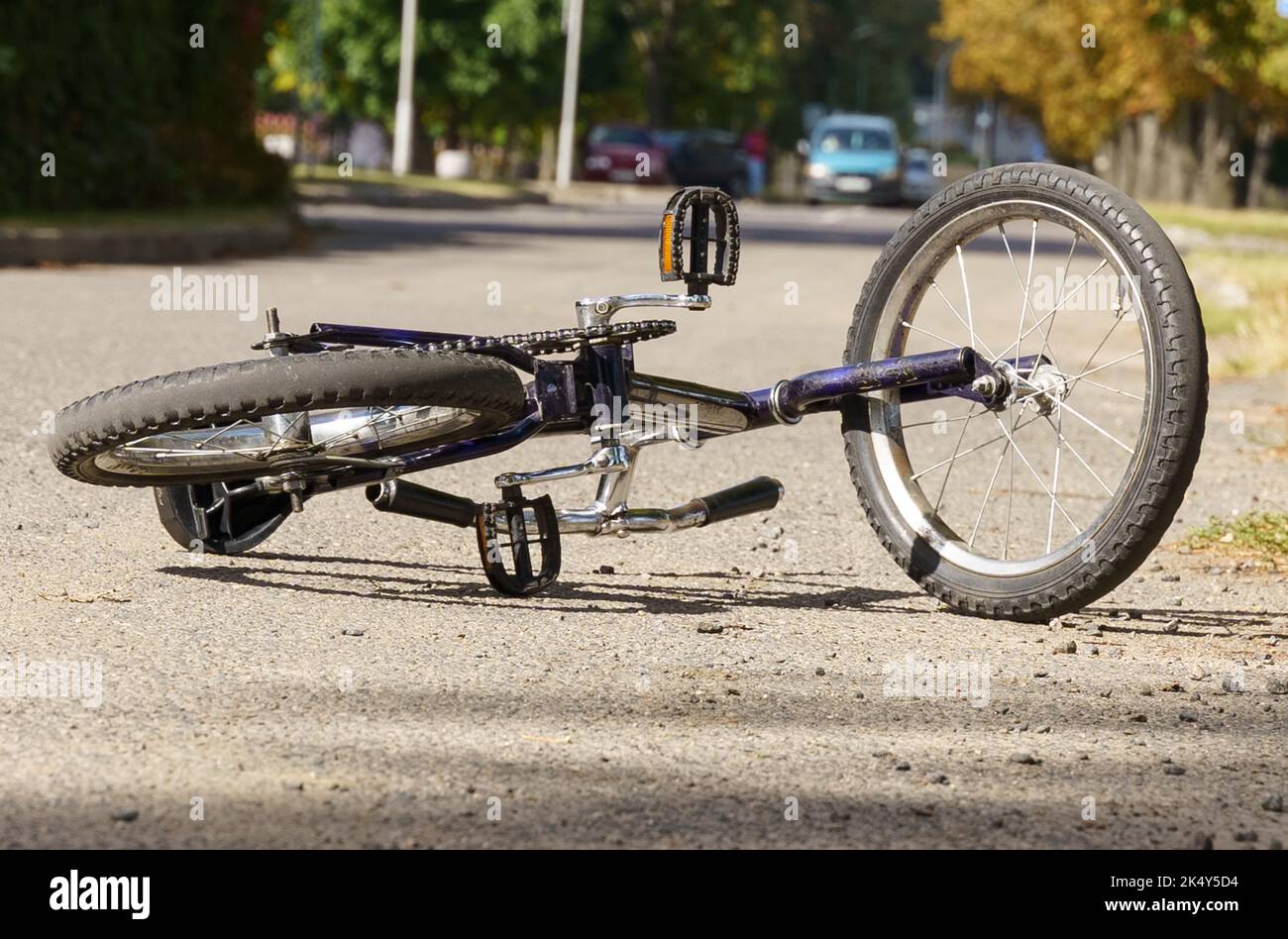 A bicycle lies on the road after a car hit a cyclist. In the background ...