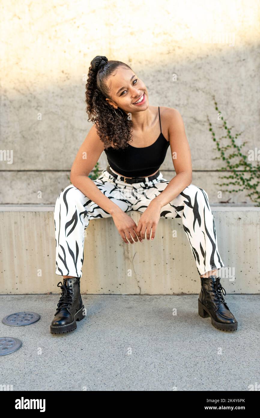 Portrait of an Edgy Young Black Woman Sitting in Front of a Concrete ...