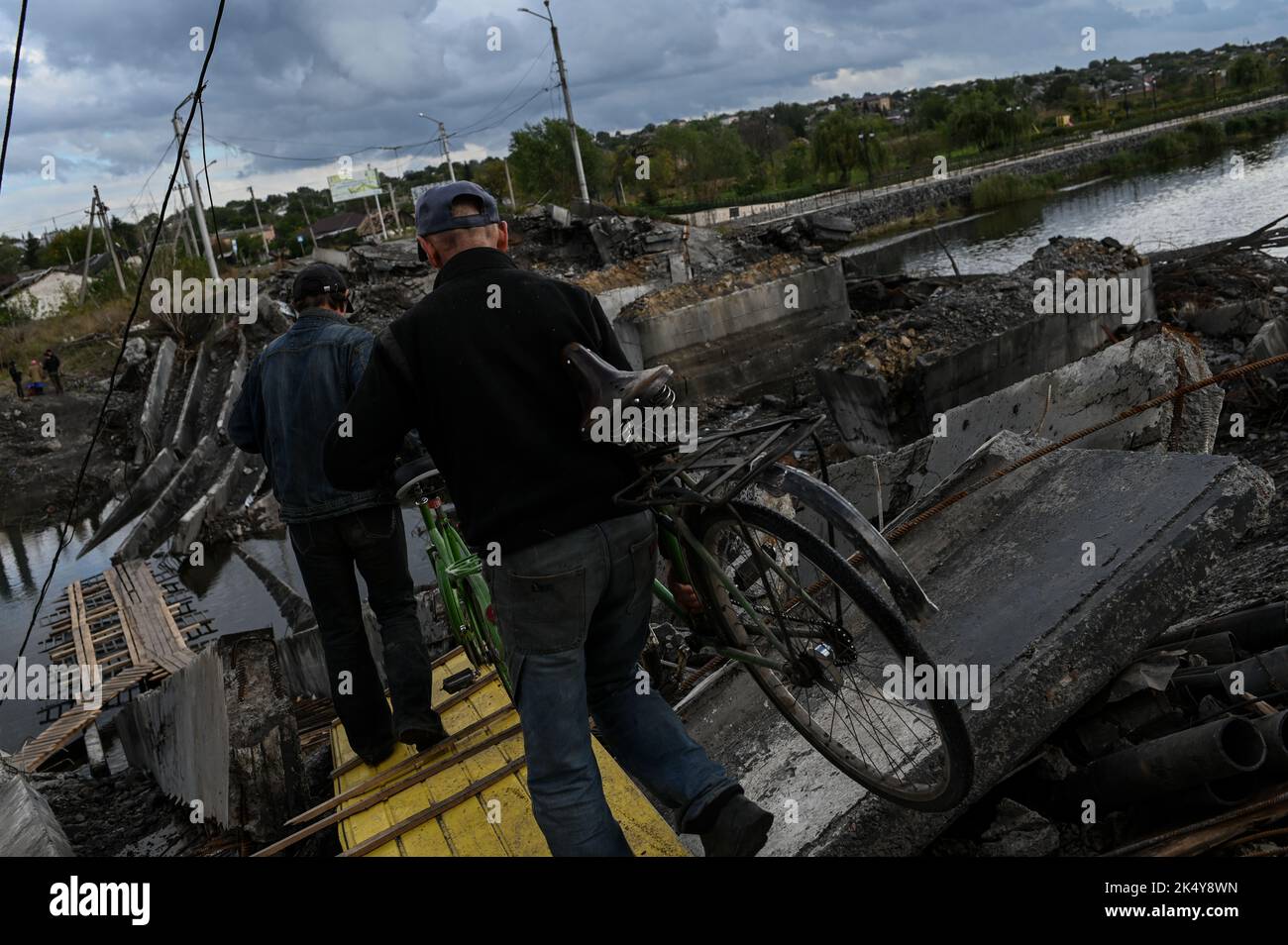 Residents of Bakhmut city cross Bakmutovka River carrying bicycles via ...