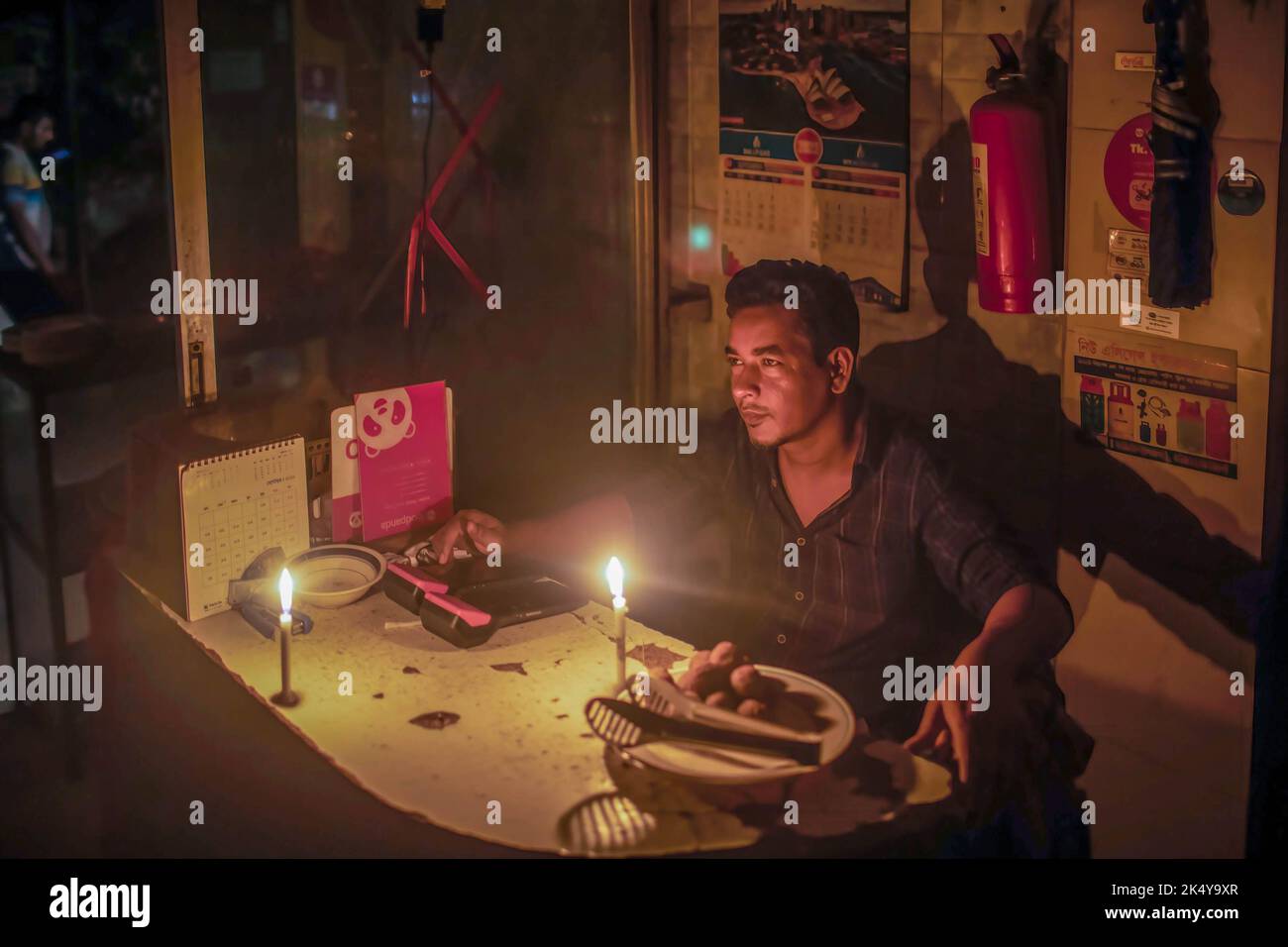 Dhaka, Bangladesh. 4th Oct, 2022. A man eats in a restaurant under candle lights during a power ...