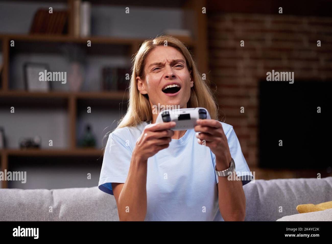 Happy woman using wireless joystick and playing video games at home ...