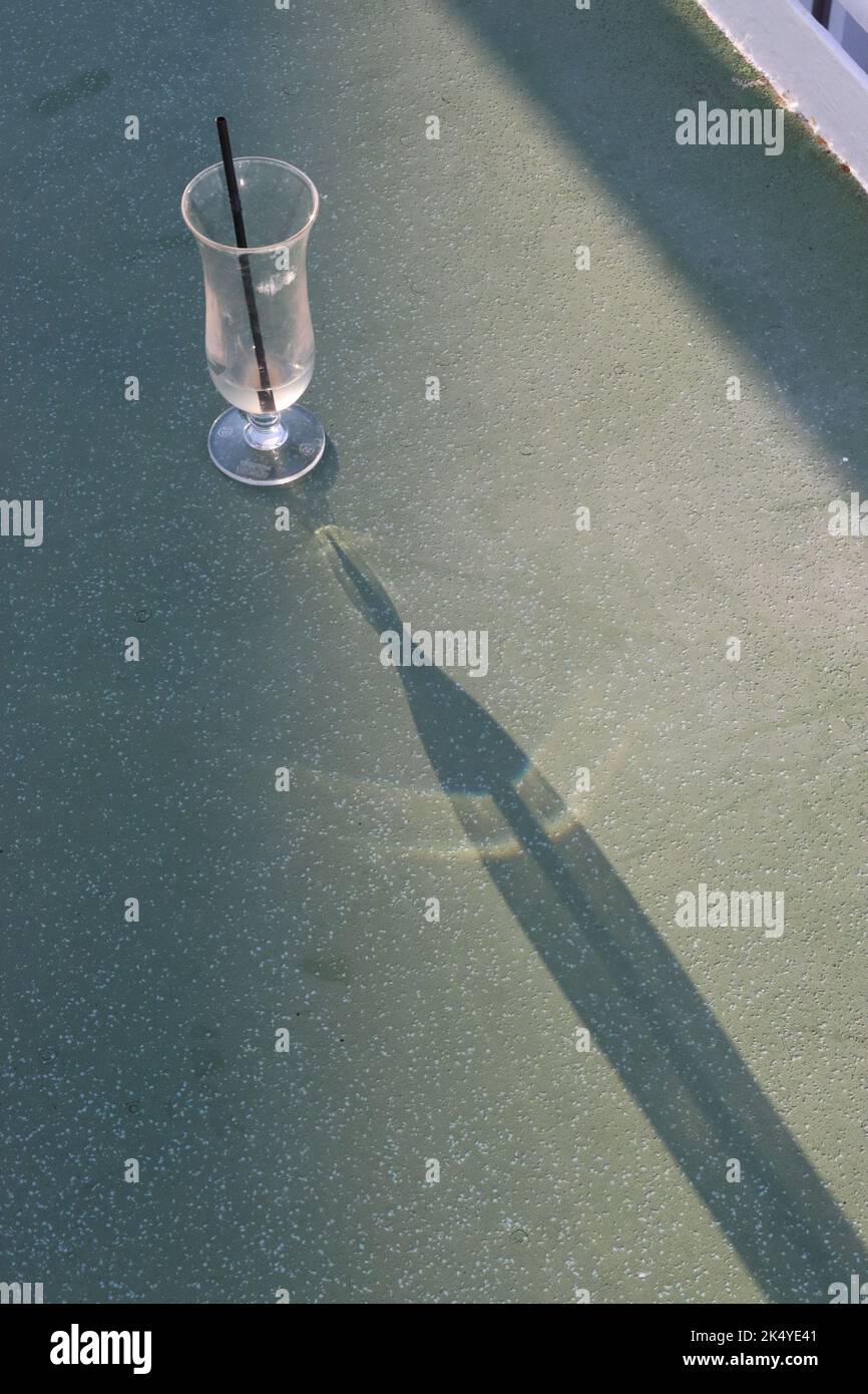 Evening sunlight casts a long shadow from a cruise guest’s drinks glass ...