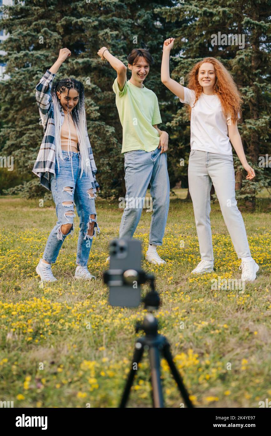 Teenagers are filming dance video with a phone in the summer park ...