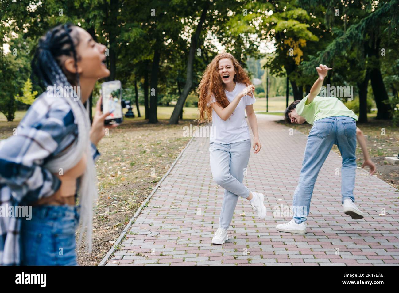 Young caucasian woman shooting her friends dancing in the park for ...