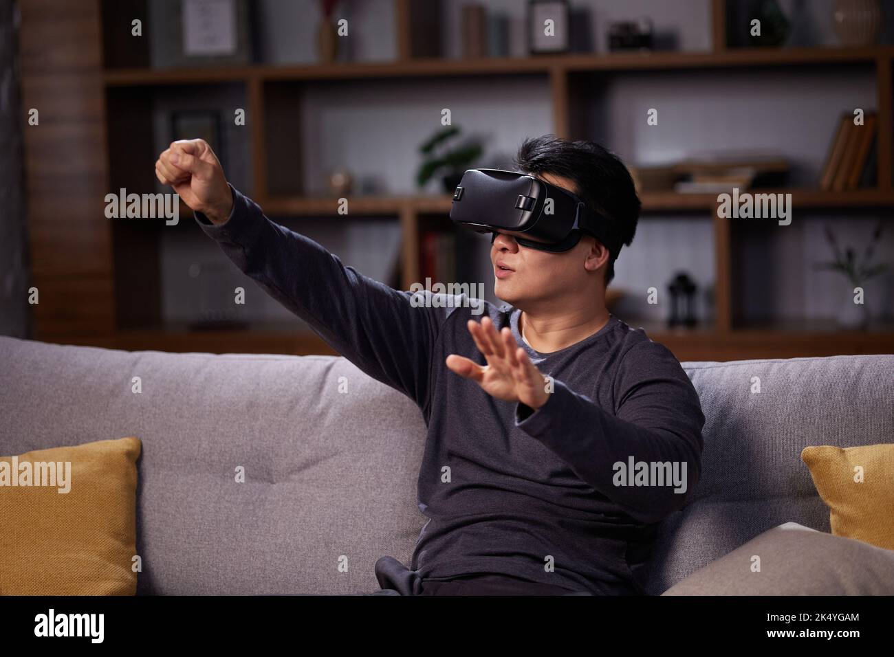 Happy Asian man using VR and playing video games at home. Joyful man ...