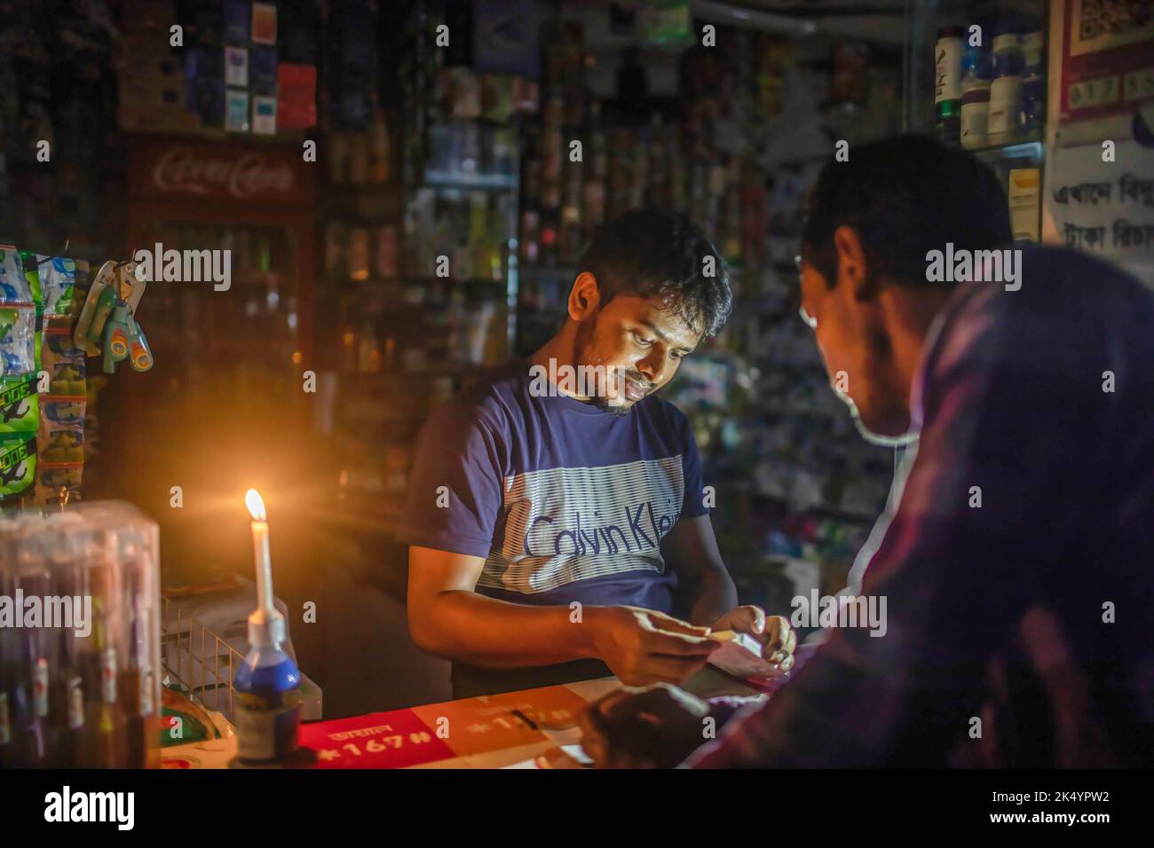 Dhaka, Bangladesh. 04th Oct, 2022. Shopkeeper working under candle ...