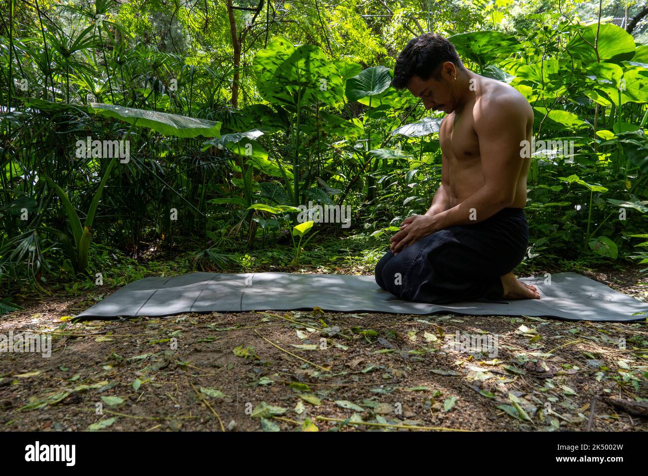 Young latin man arranging his yoga mat, inside a forest on a plain ...