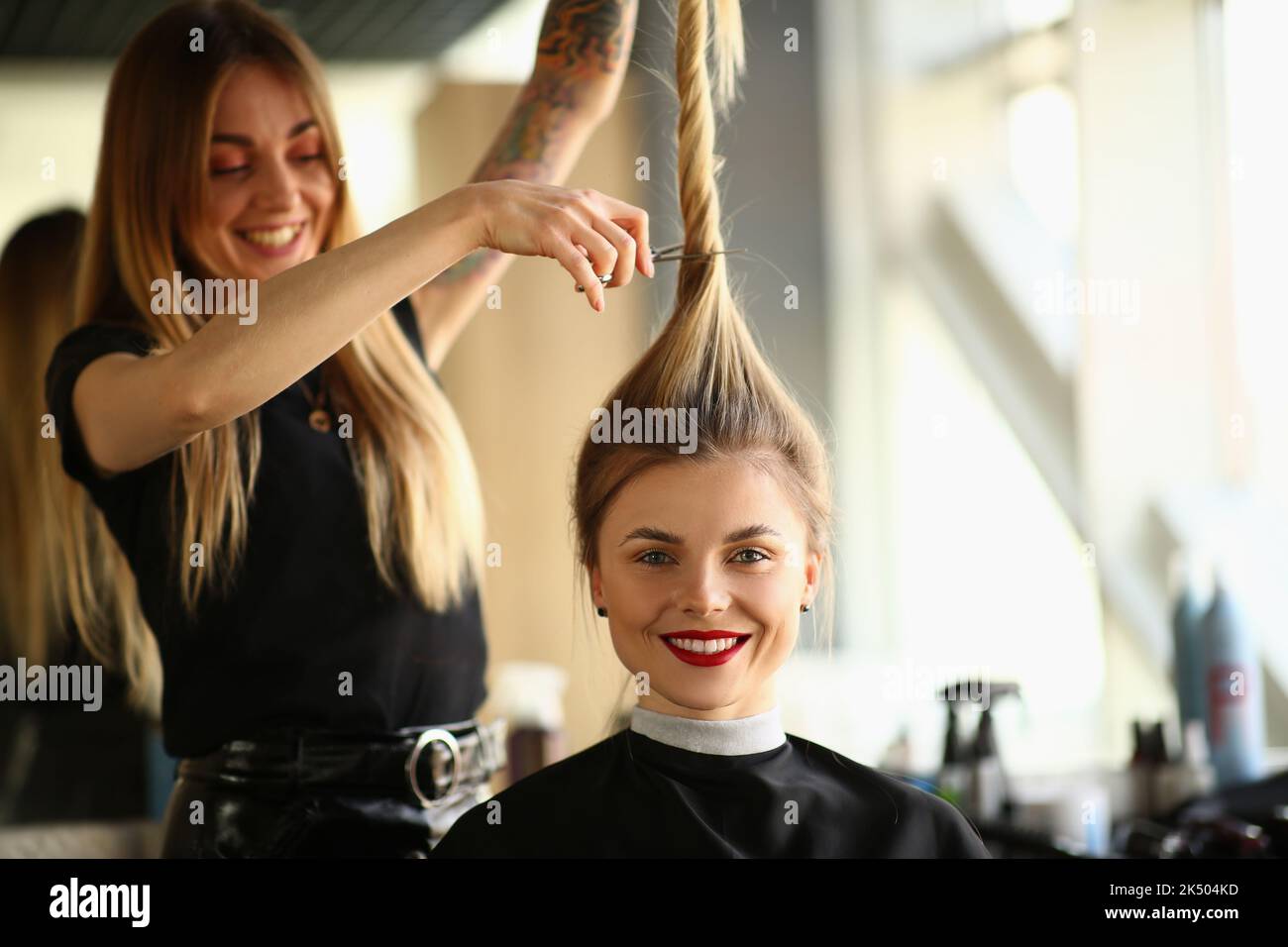 Professional female hairdresser stylist cuts hair of female client in ...