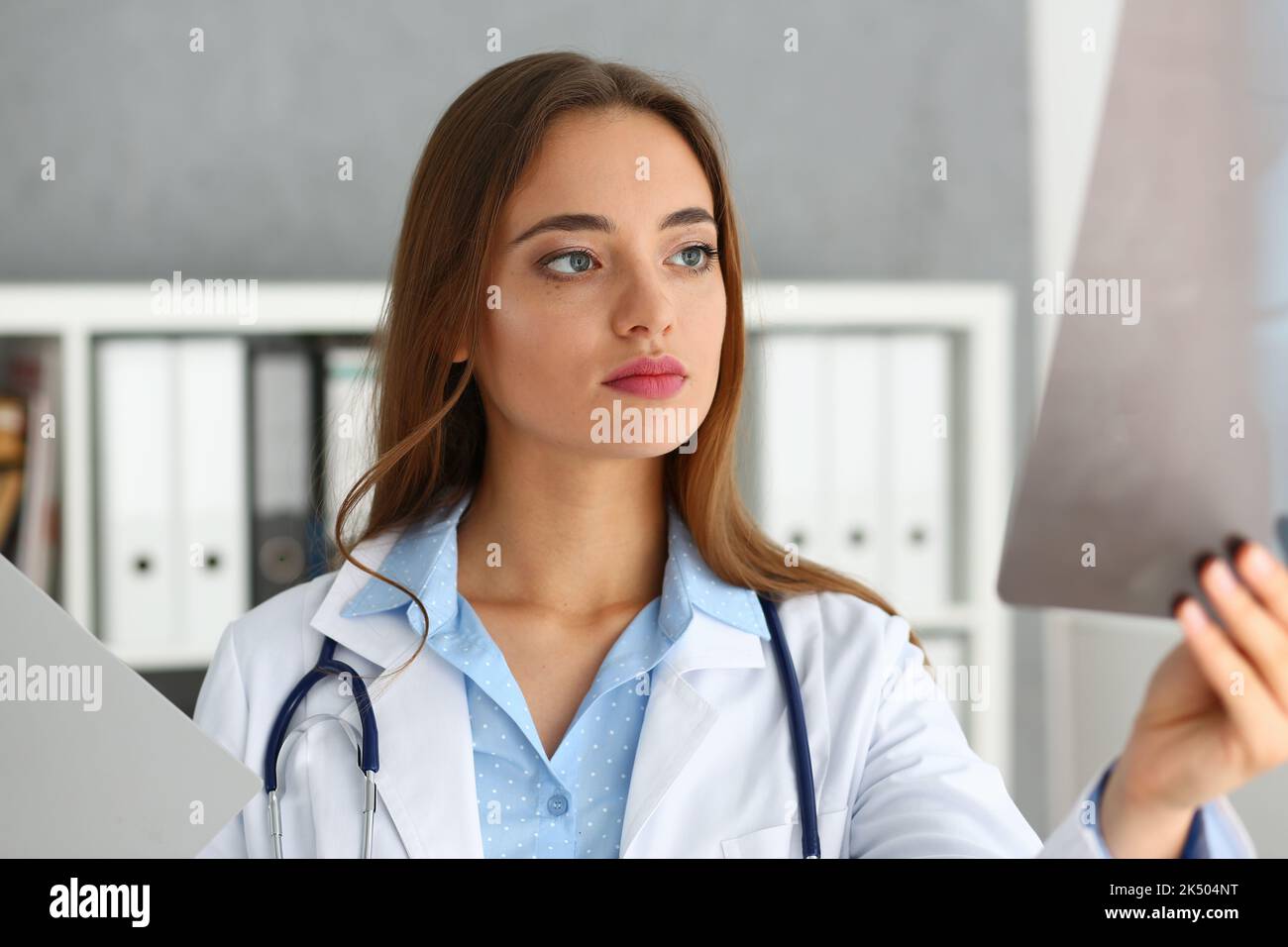 Young professional beautiful female doctor examining x-ray of patient ...