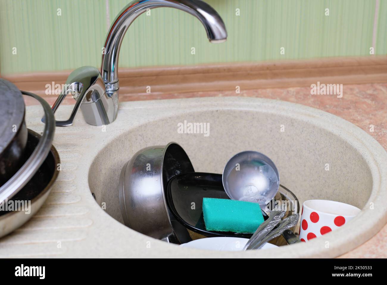 dirty dishes and kitchen utensils in a sink. messy kitchen. cluttered ...