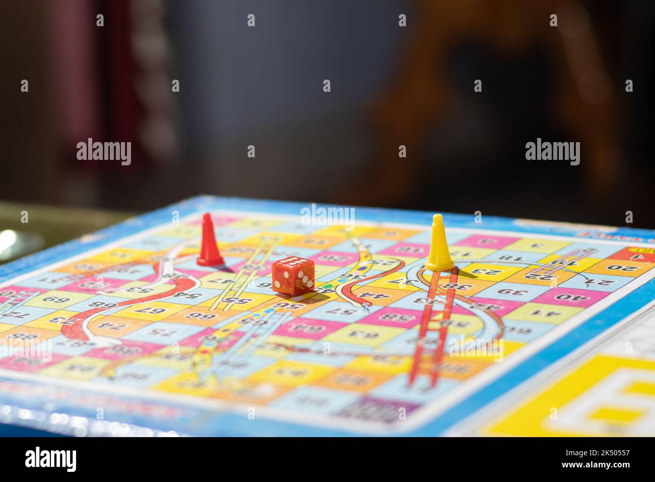 Selective focus on a dice in a snakes and ladders indoor board game ...