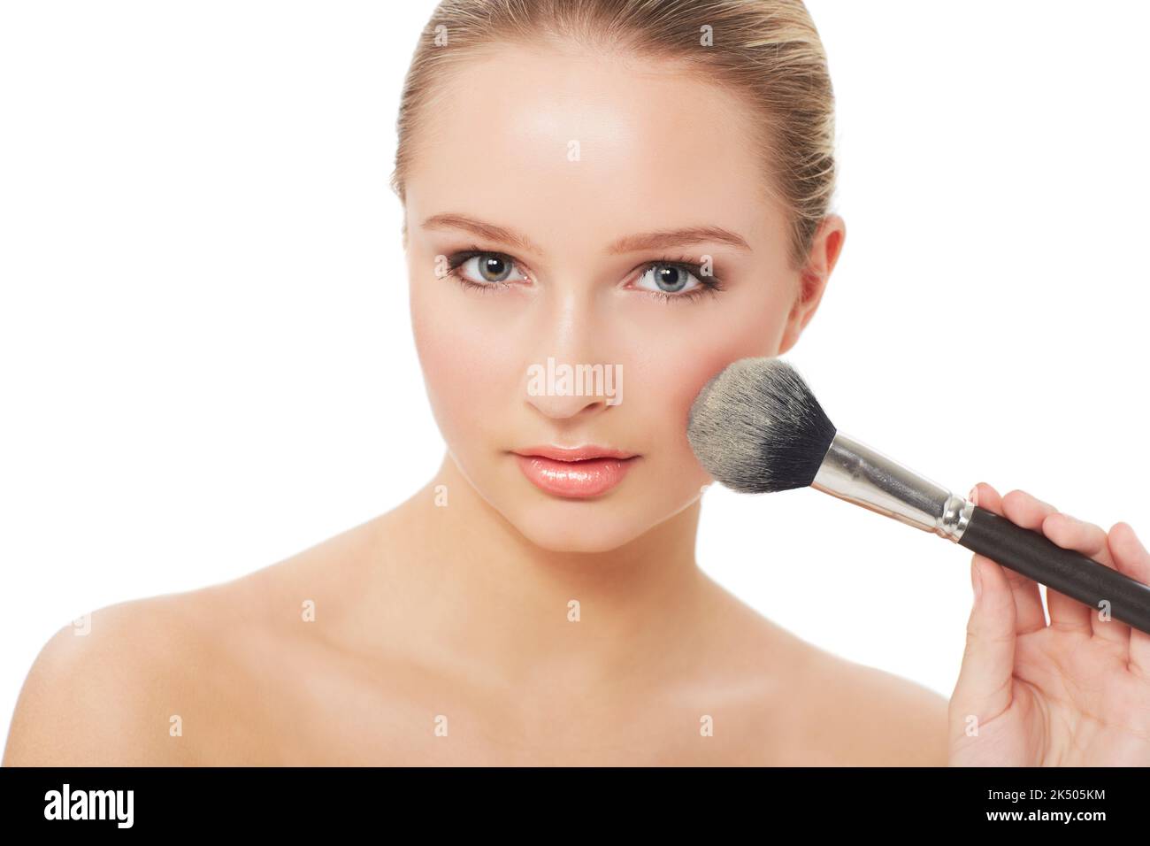 Show-stopping beauty. A beautiful young woman applying blush to her ...