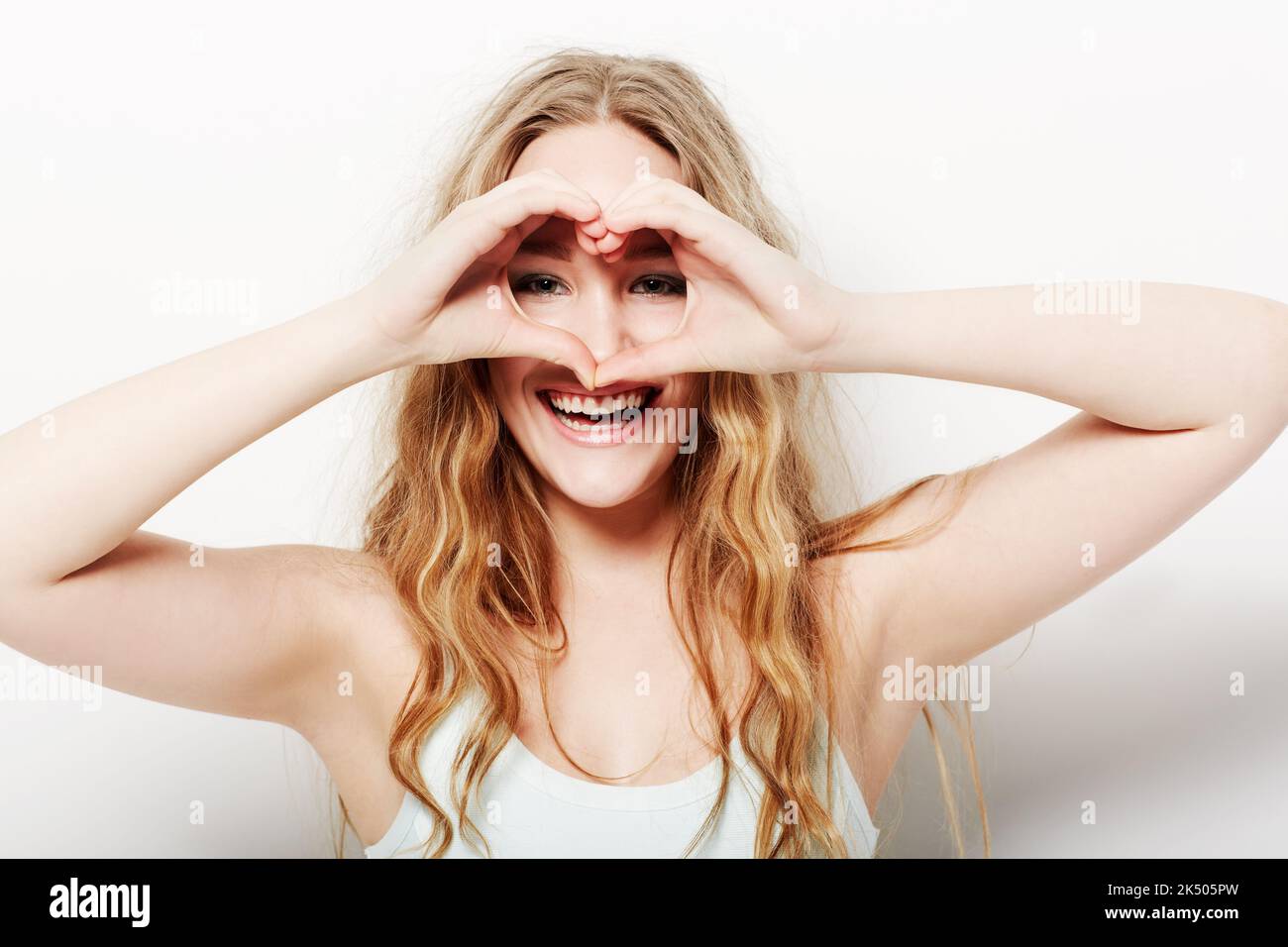 Showing You Some Love Smiling Young Woman Making A Heart Shape With