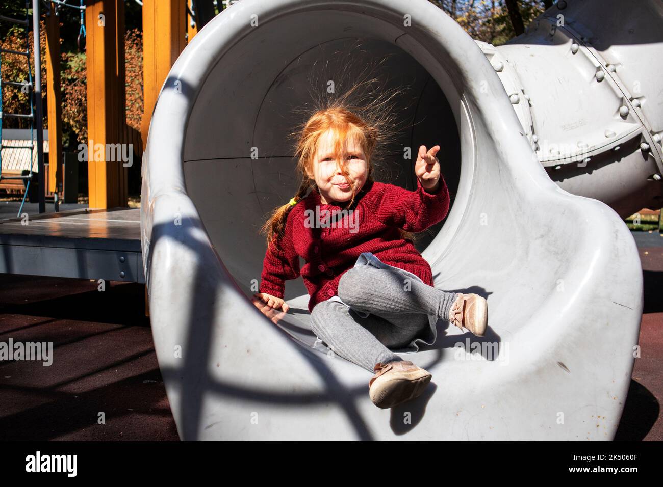 a red-haired little girl rolled down a pipe slide Stock Photo - Alamy
