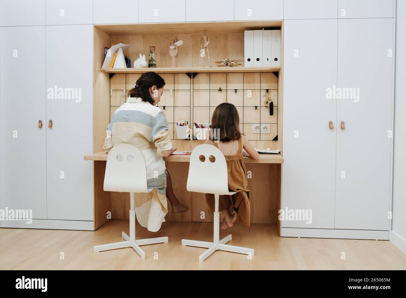 Young mom helping her little cute daughter do her homework. Sitting at ...
